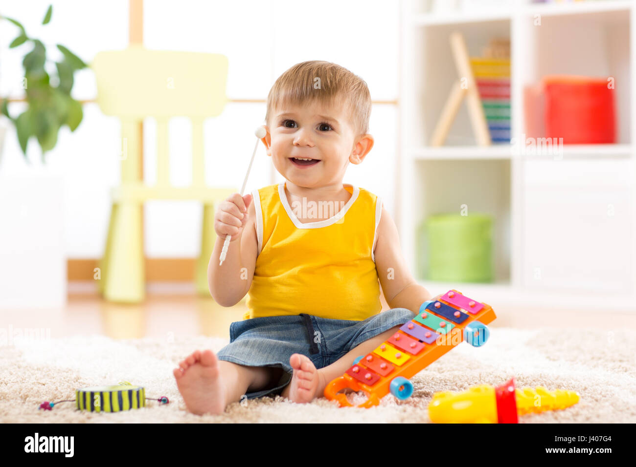 Cheerful little boy plays musical toys Stock Photo - Alamy