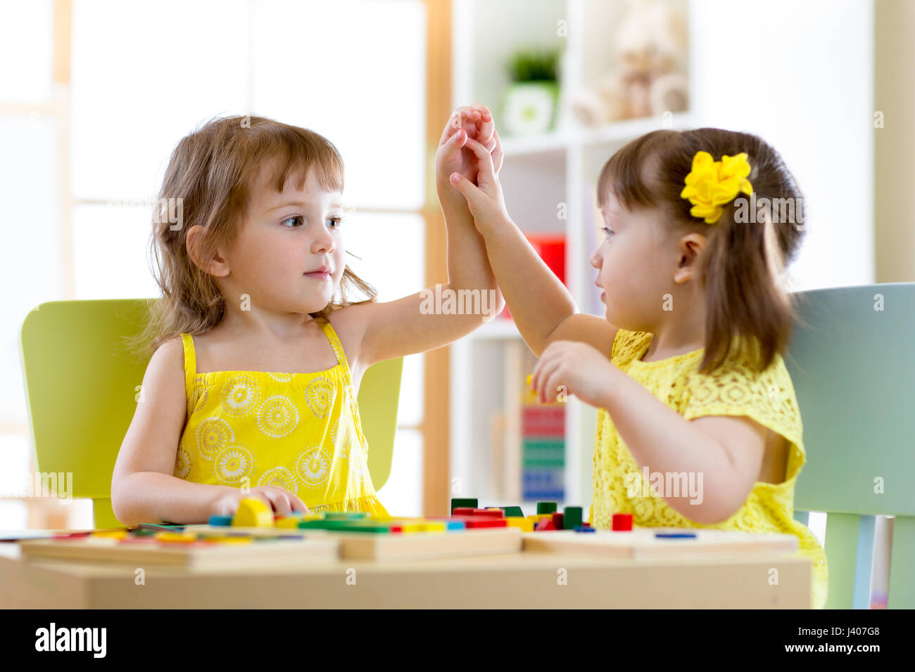 Two cute little girls playing together in daycare Stock Photo - Alamy