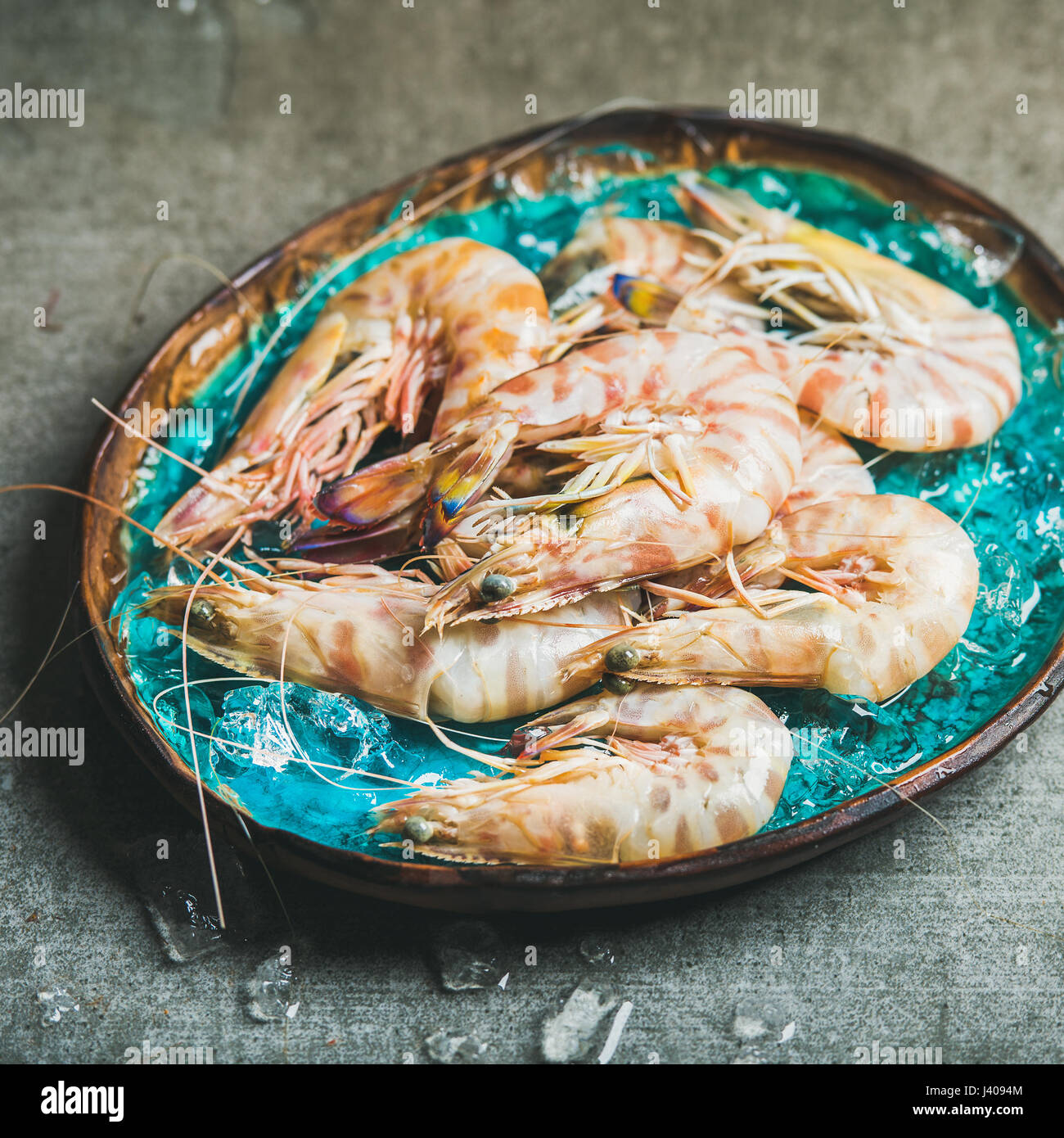 Raw uncooked tiger prawns on chipped ice in blue tray Stock Photo - Alamy