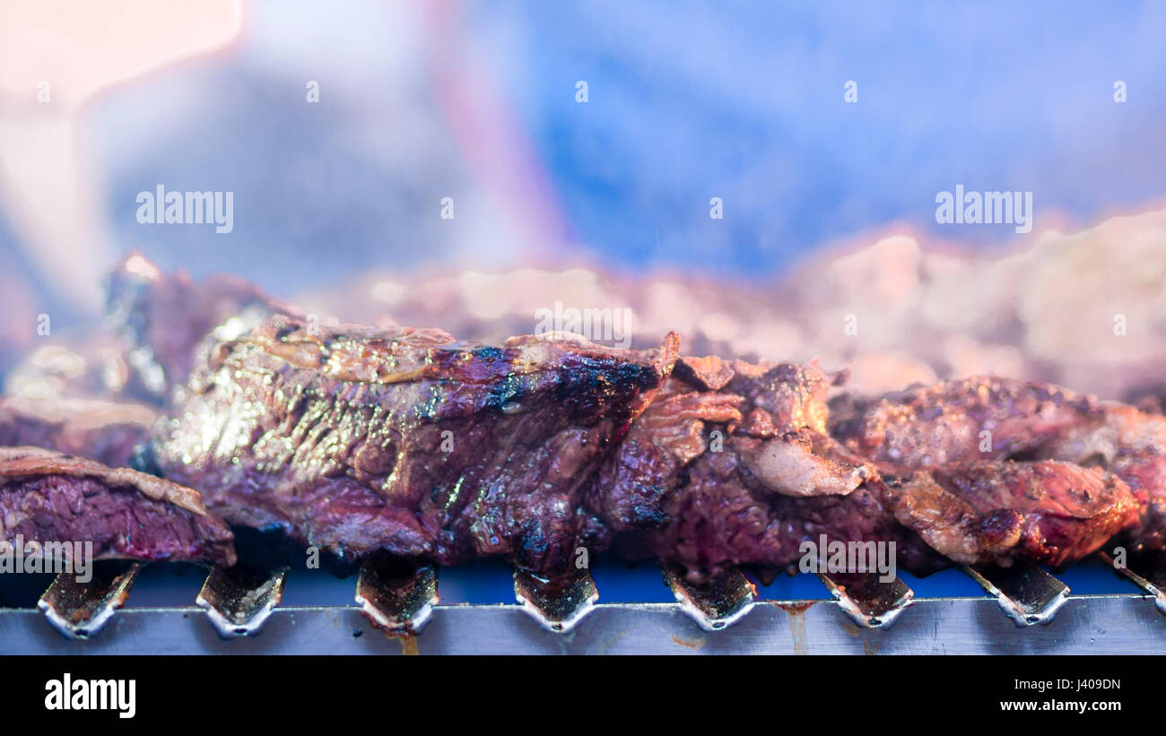 Grilling red meat and sausages at sunset outdoors gathering with ...