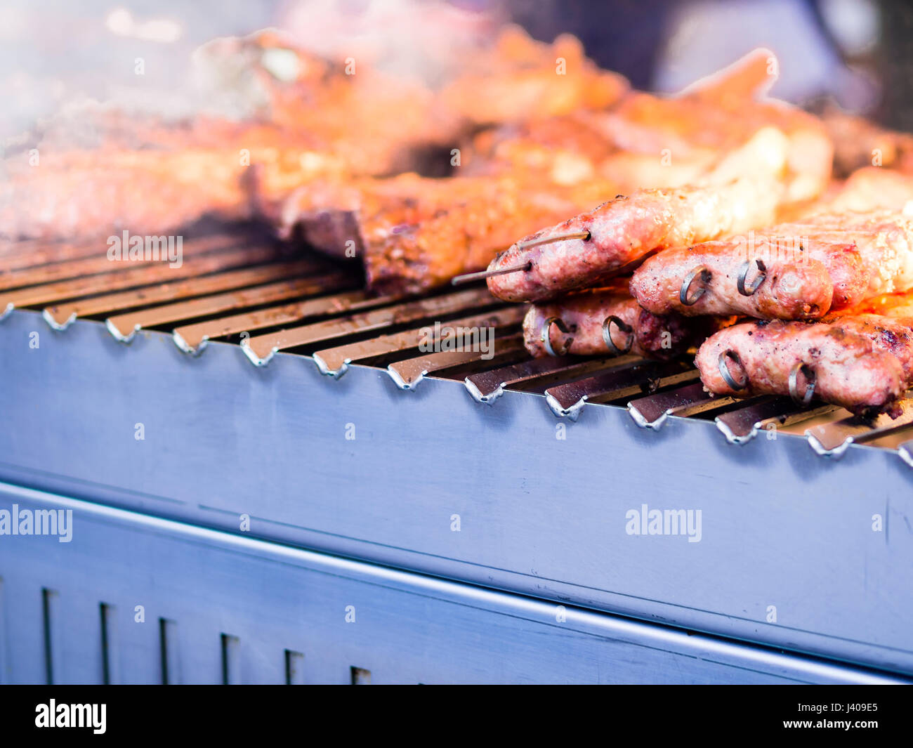 Grilling red meat and sausages at sunset outdoors gathering with ...