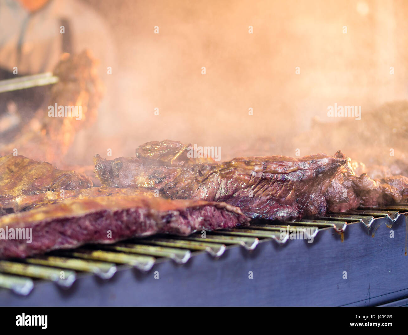 Grilling red meat and sausages at sunset outdoors gathering with ...