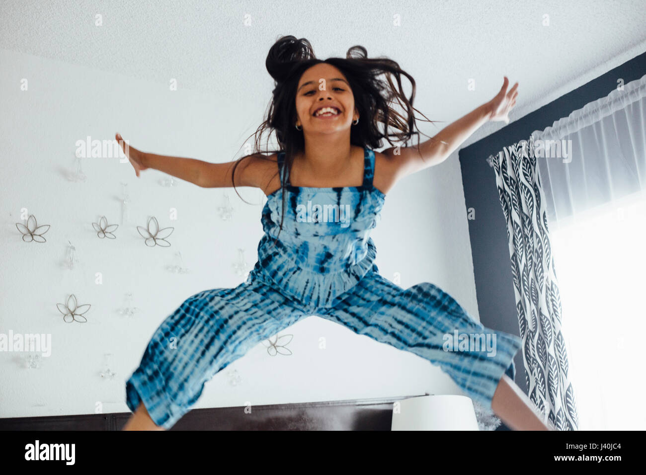 Girl jumping in mid air smiling Stock Photo - Alamy