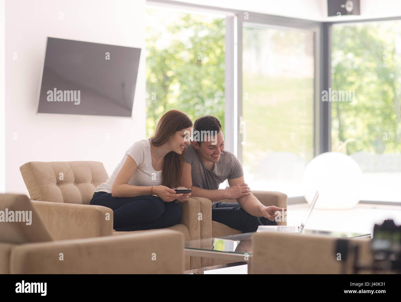 Young couple relaxing at luxurious home with tablet and laptop ...