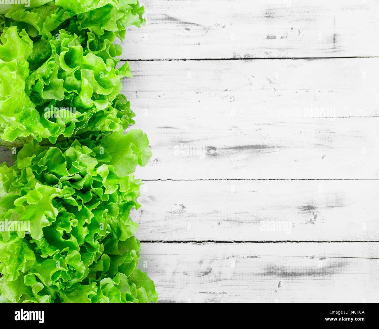 Fresh lettuce leaves border over white wooden plank background. Organic ...