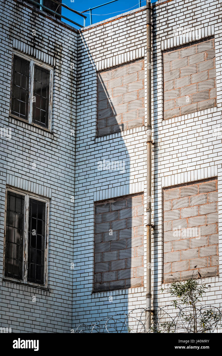 Old, white factory/office building boarded up waiting demolition ...