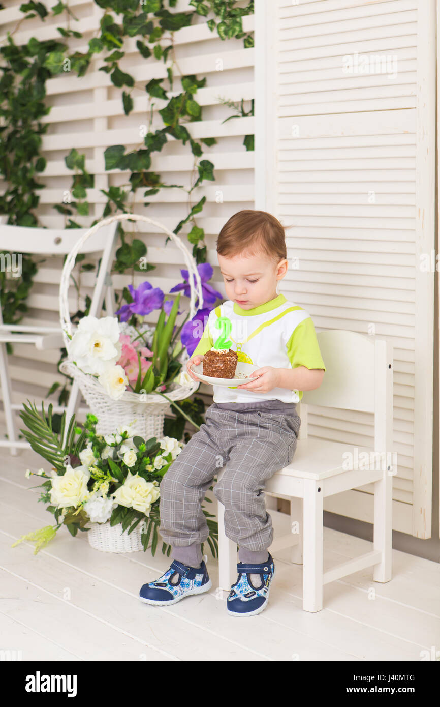 Happy little kid boy celebrating his birthday holds piece of cake ...