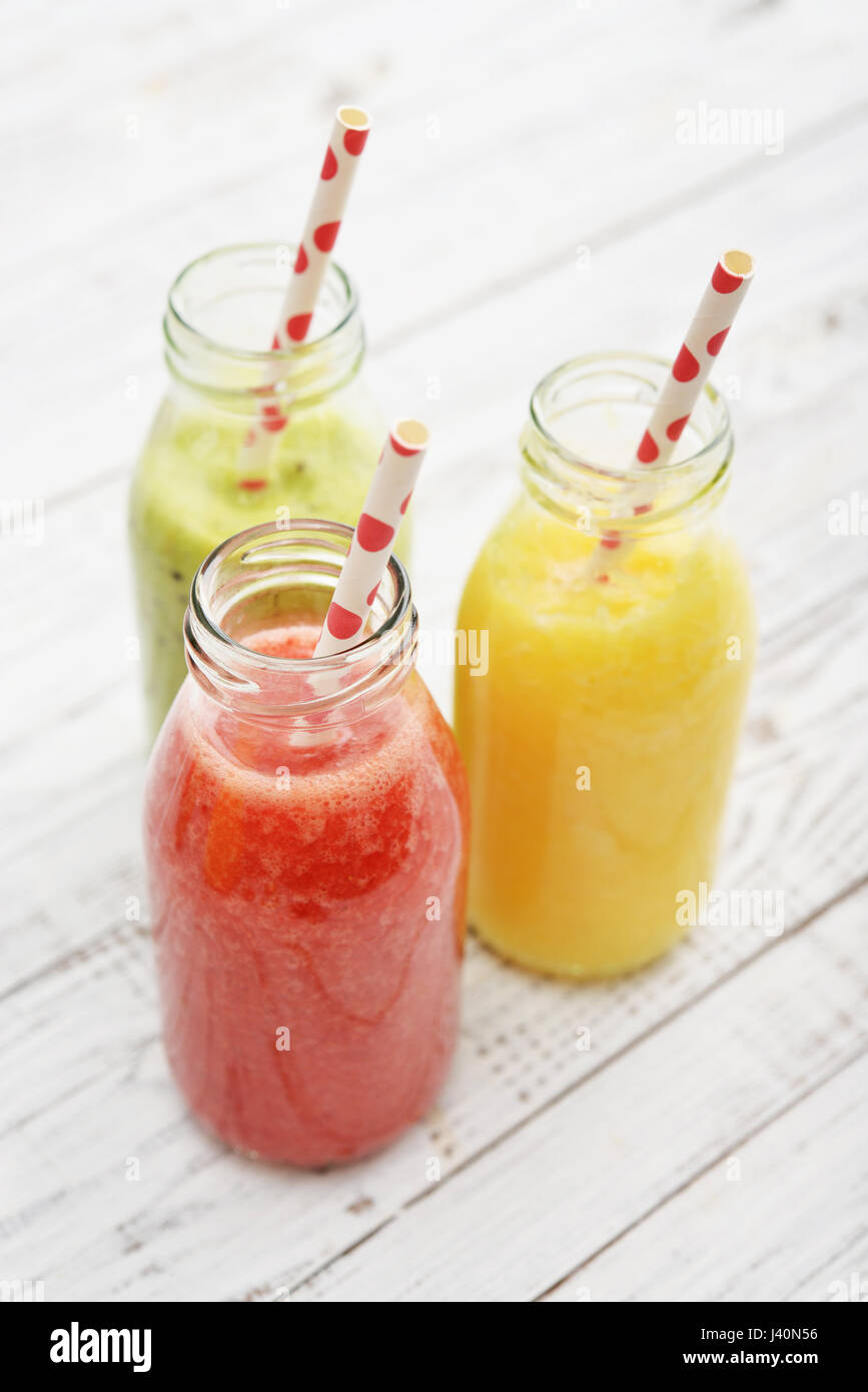 Fruit smoothies in retro bottles with drink straws on light wooden ...
