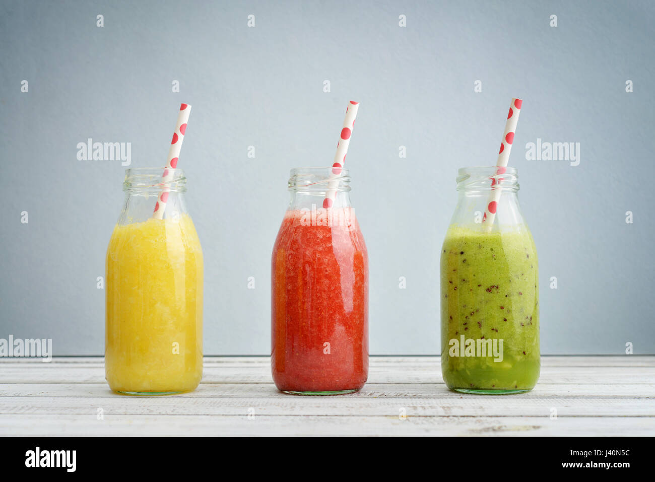 Fruit smoothies in retro bottles with drink straws on blue background ...