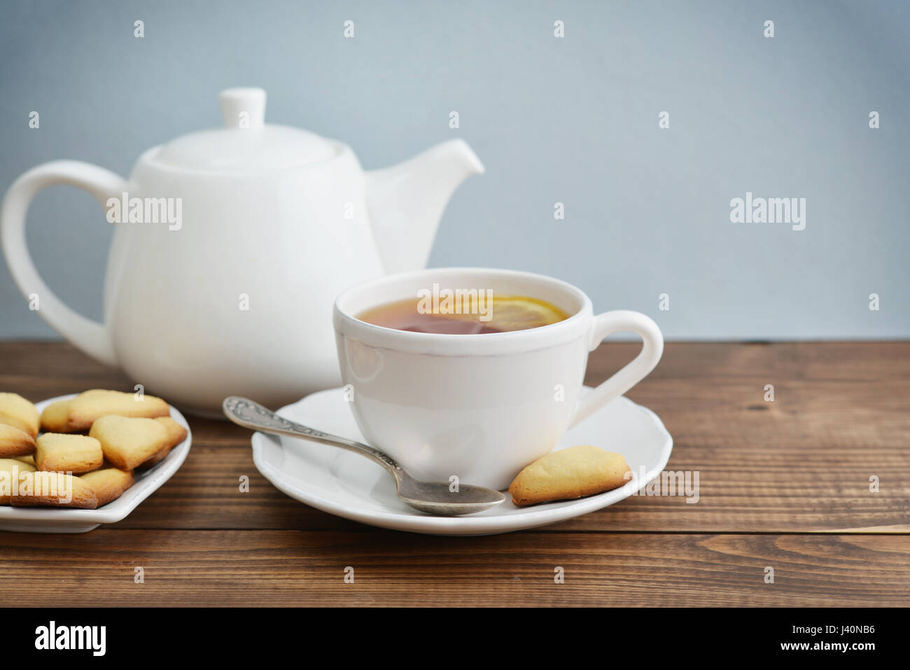 Cup of tea and cookies with teapot over blue background Stock Photo - Alamy