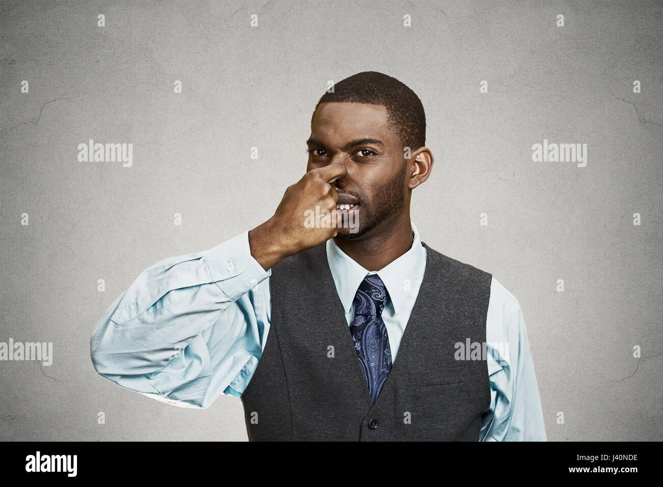 Closeup portrait young executive man, disgust on face, pinches his nose ...