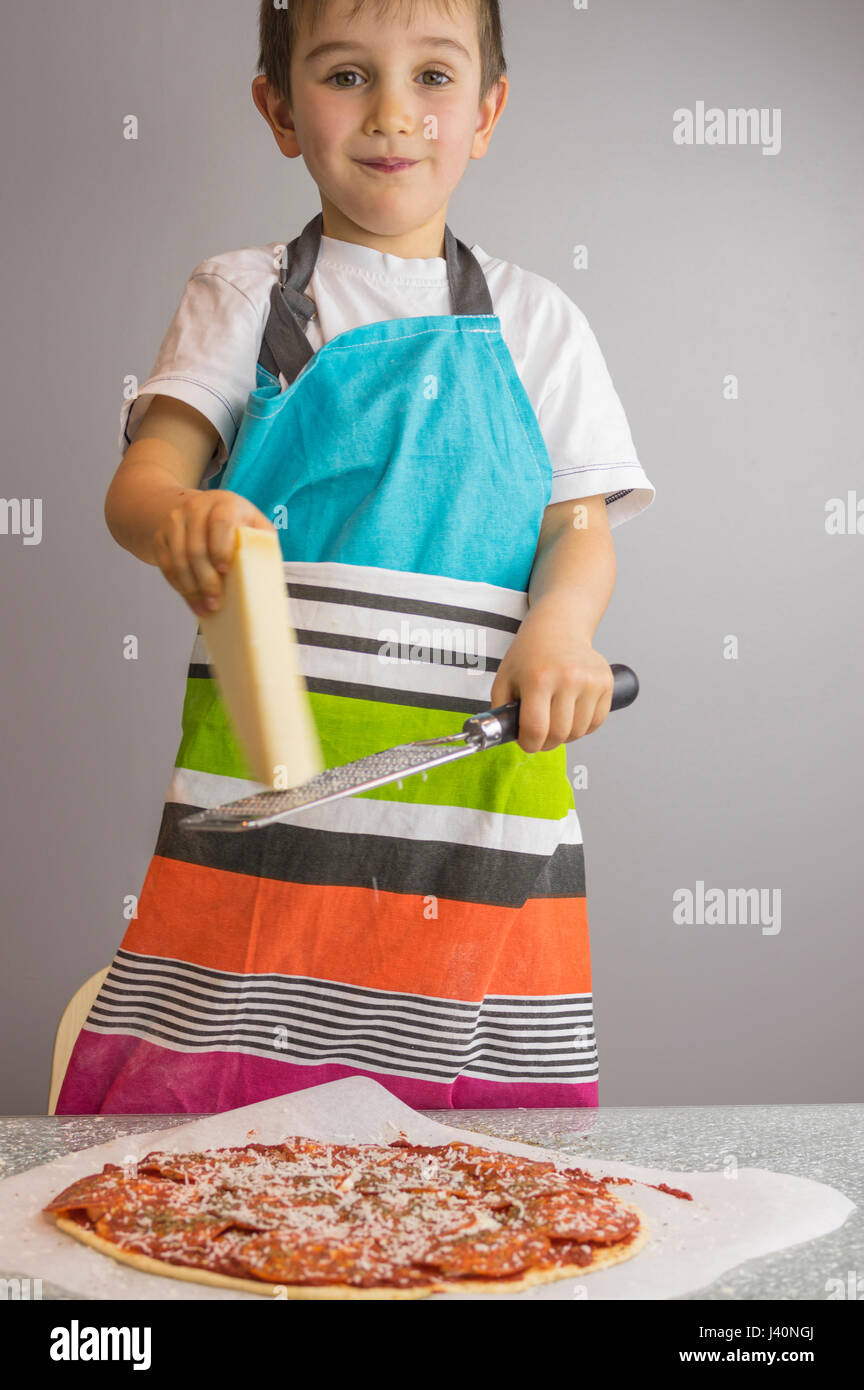 Little boy is making pizza, scrape cheese with grater Stock Photo - Alamy