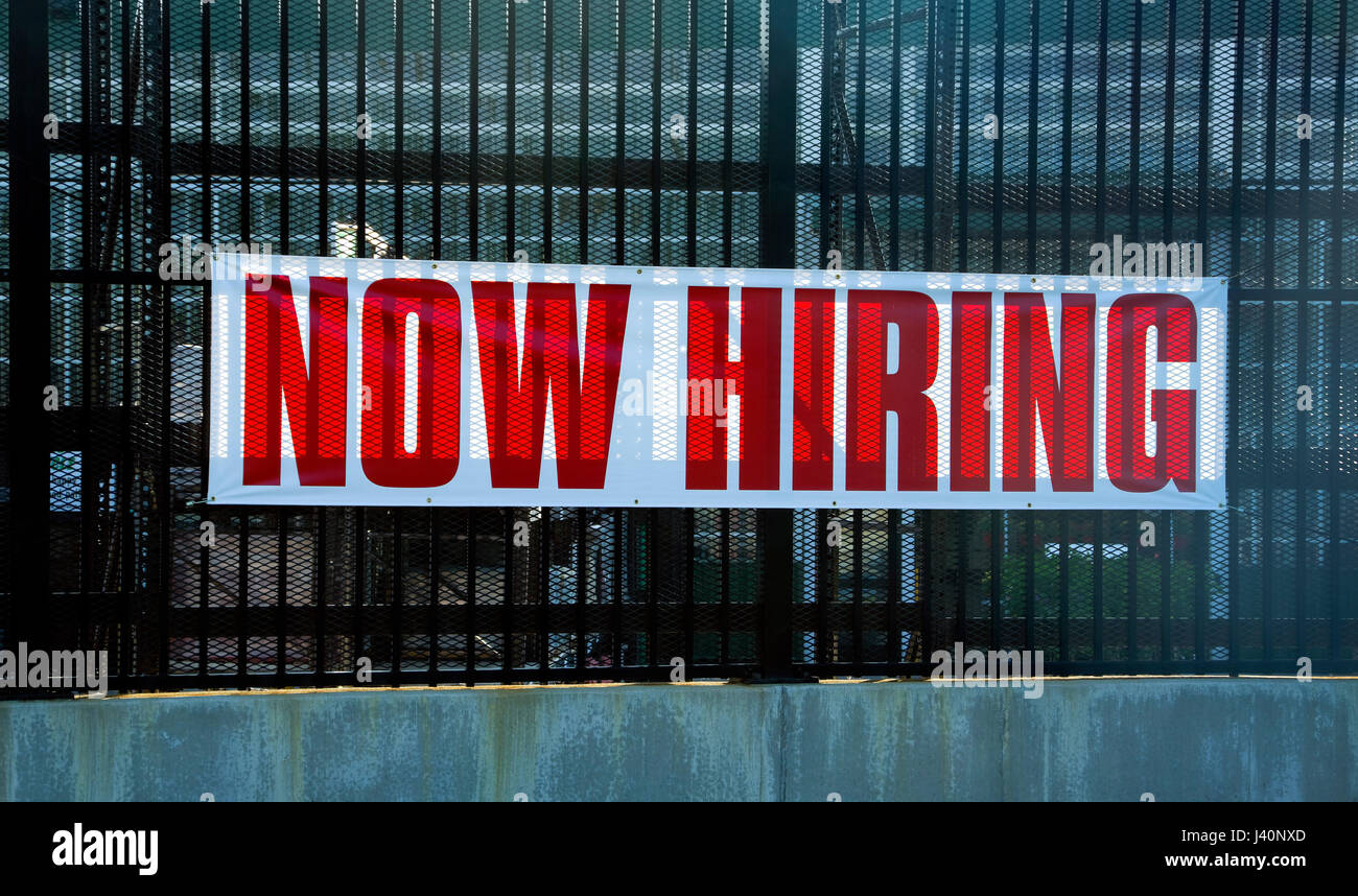 Now Hiring, help wanted sign on industrial fence Stock Photo - Alamy