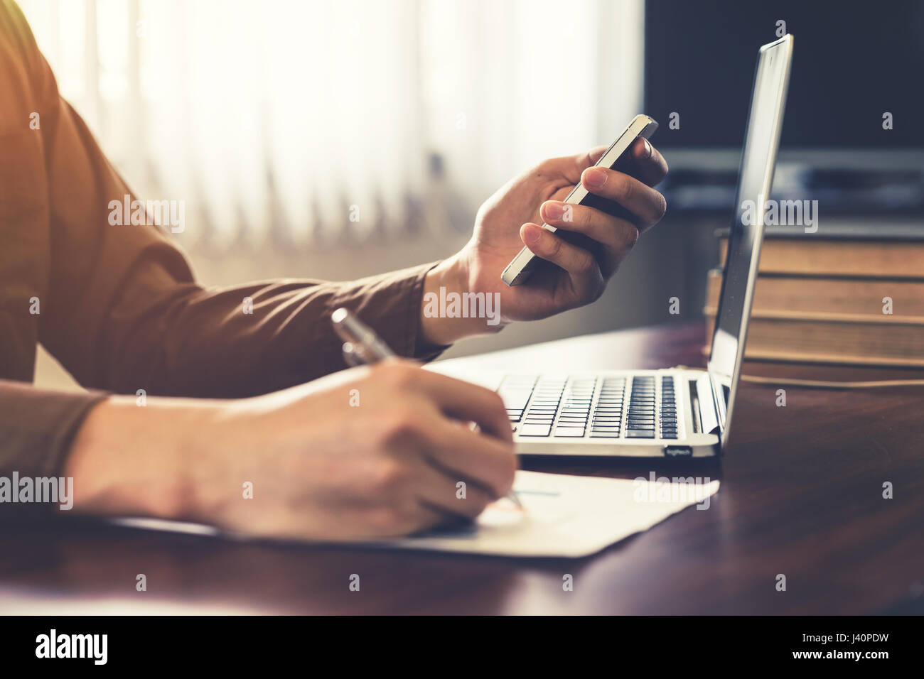 Young business man hand using phone and writing paper in the office ...