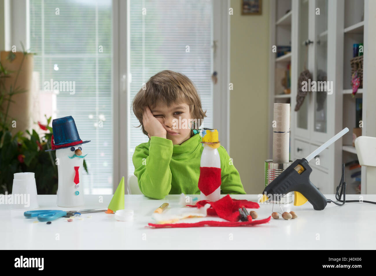 Little boy being extremely bored by making homemade do-it-yourself toys ...