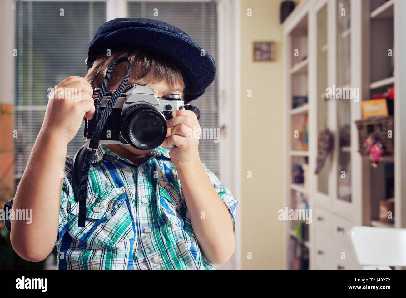Cute little boy in retro outfit taking pictures with old film camera ...
