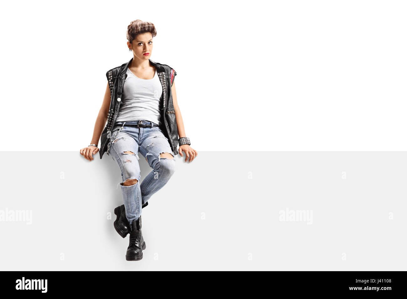 Punk girl sitting on a panel and looking at the camera isolated on ...