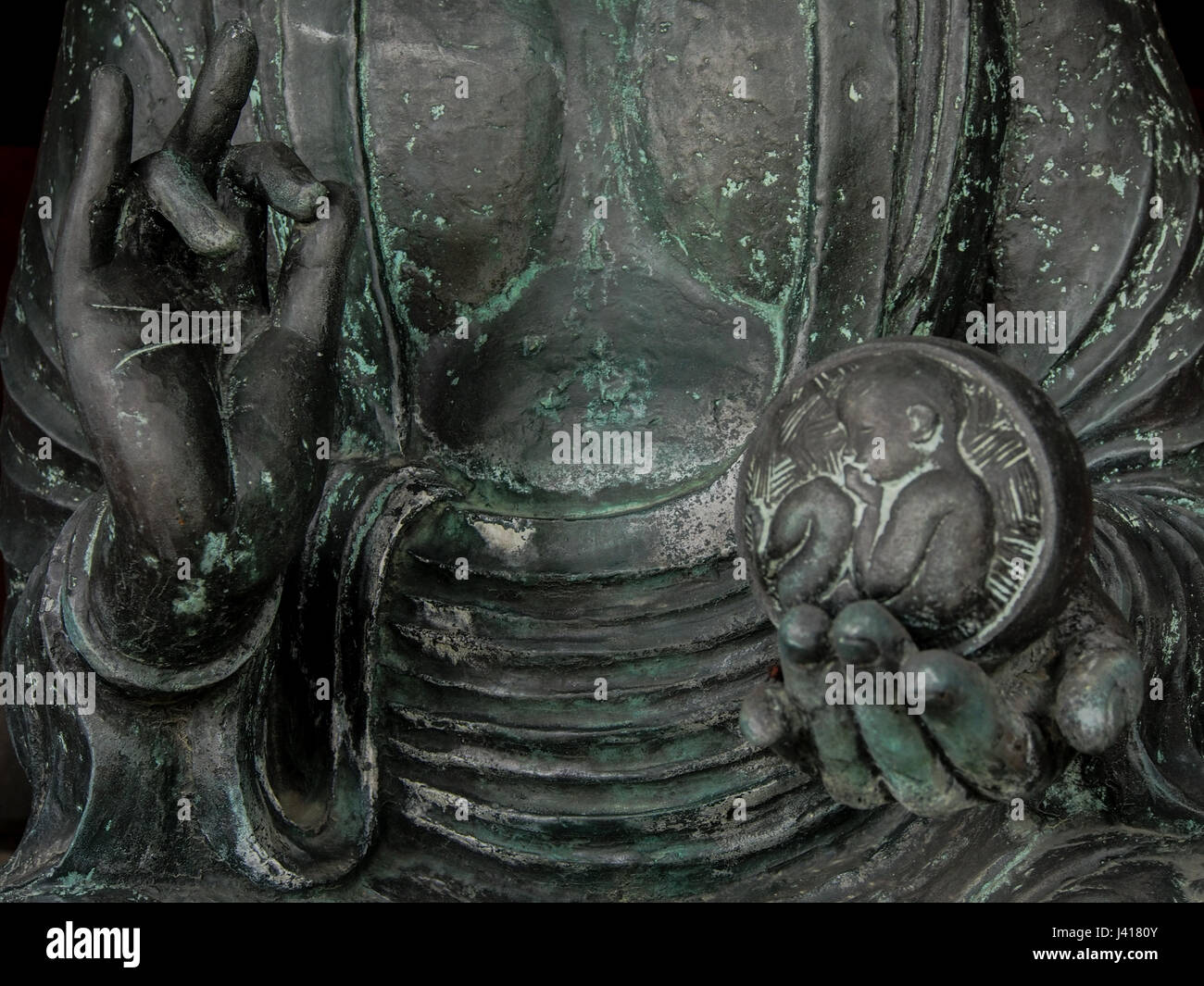 Statue of Buddhist deity, one hand in blessing mudra, the other holding ...