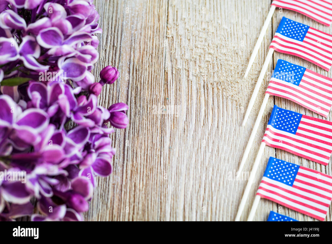 Fresh spring purple lilac and miniature flags on wooden board with room ...