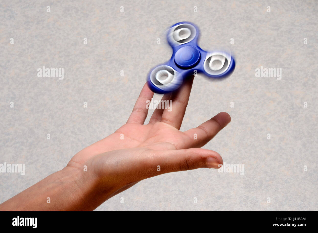Blue Hand spinner, fidgeting hand toy rotating on child's hand Stock ...