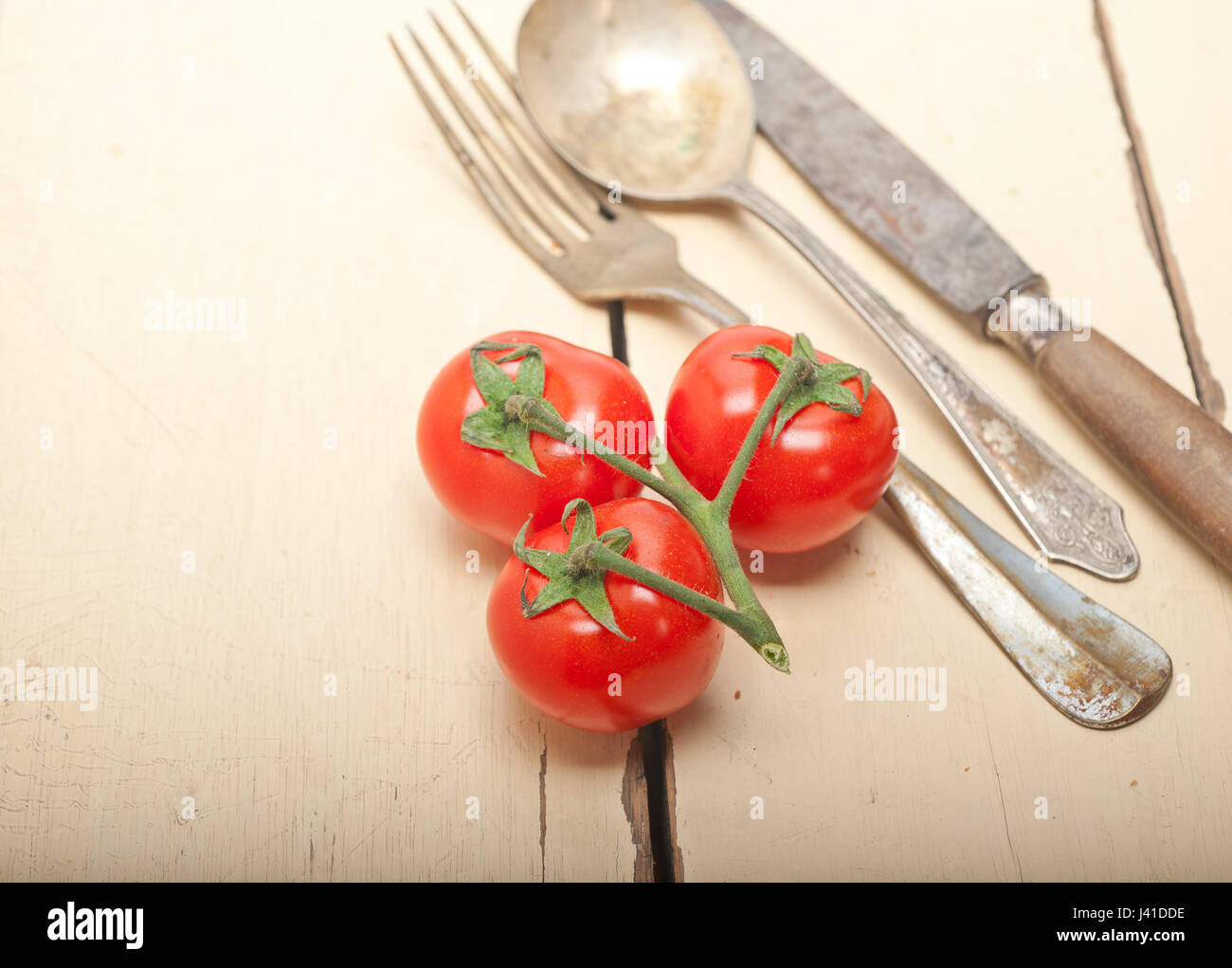 ripe cherry tomatoes cluster over white rustic wood table Stock Photo ...