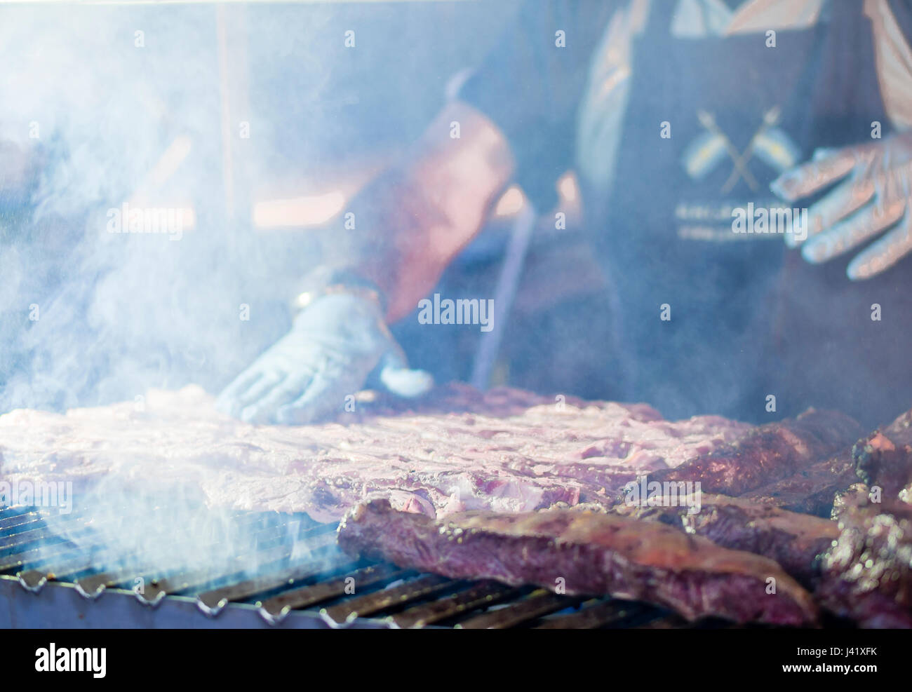 Grilling red meat and sausages at sunset outdoors gathering with ...