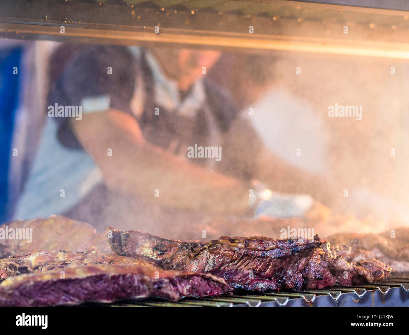 Grilling red meat and sausages at sunset outdoors gathering with ...