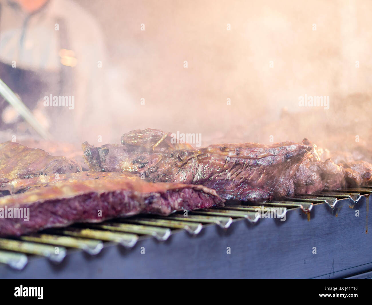 Grilling red meat and sausages at sunset outdoors gathering with ...