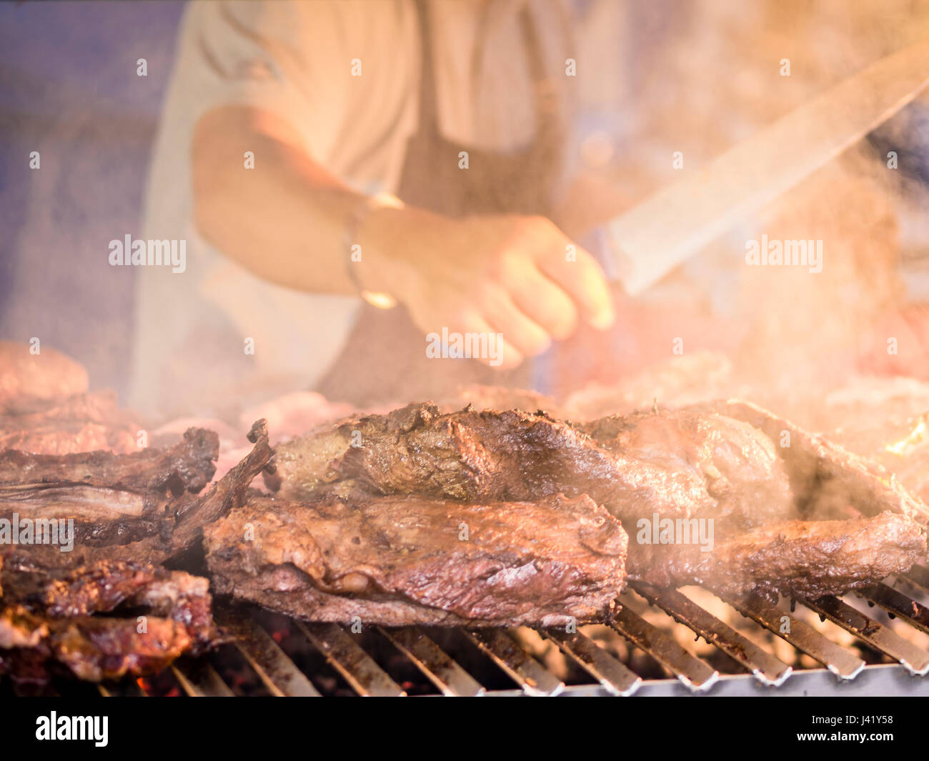 Grilling red meat and sausages at sunset outdoors gathering with ...