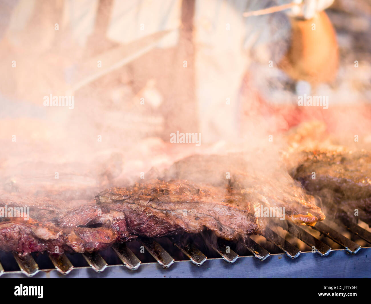 Grilling red meat and sausages at sunset outdoors gathering with ...