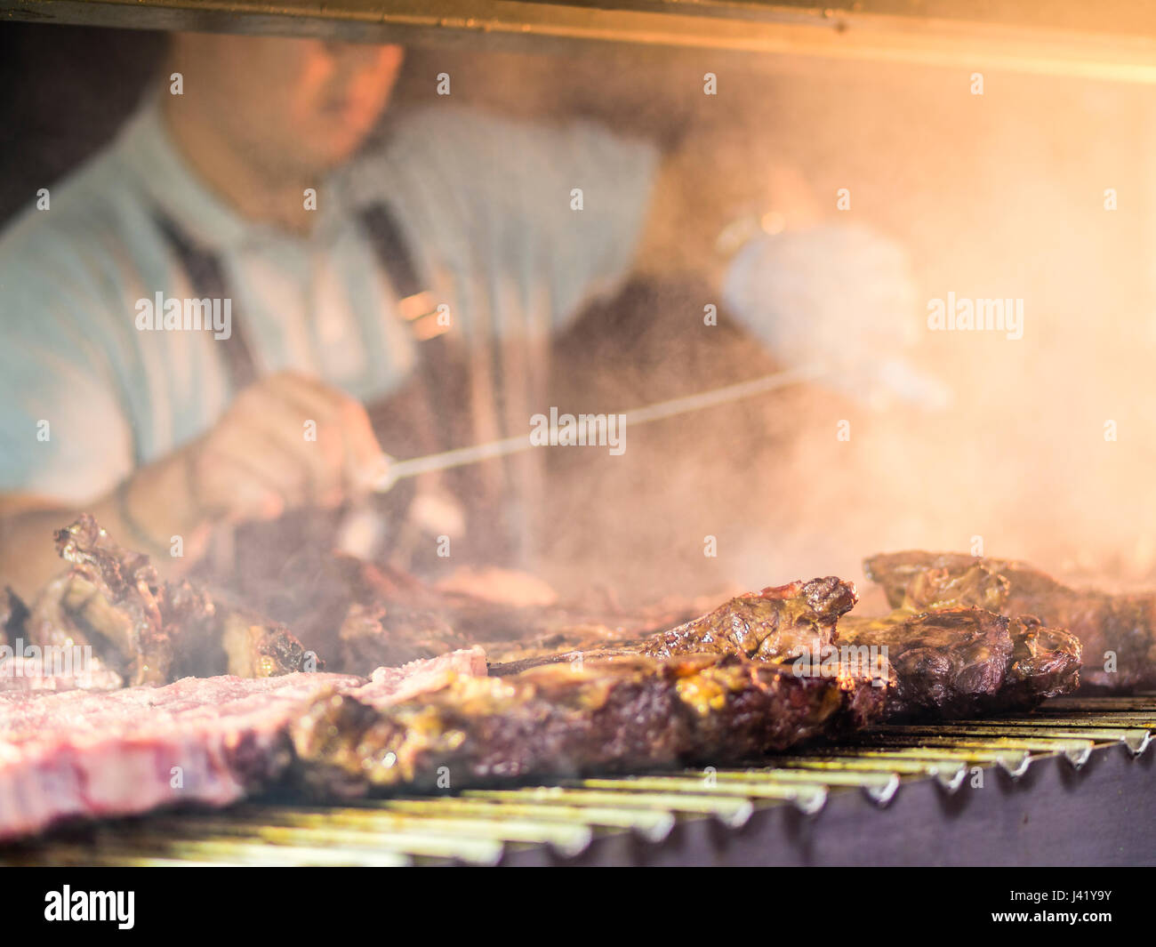 Grilling red meat and sausages at sunset outdoors gathering with ...