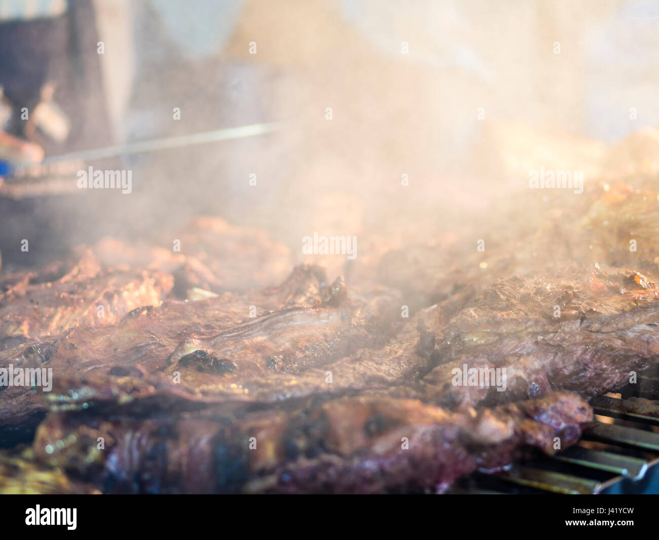 Grilling red meat and sausages at sunset outdoors gathering with ...