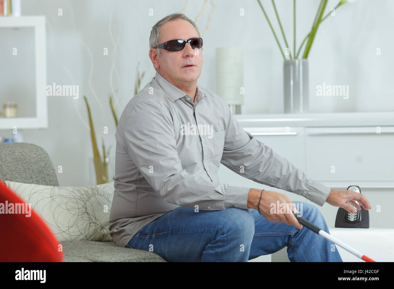 Blindman at home wearing glasses and holding stick Stock Photo - Alamy