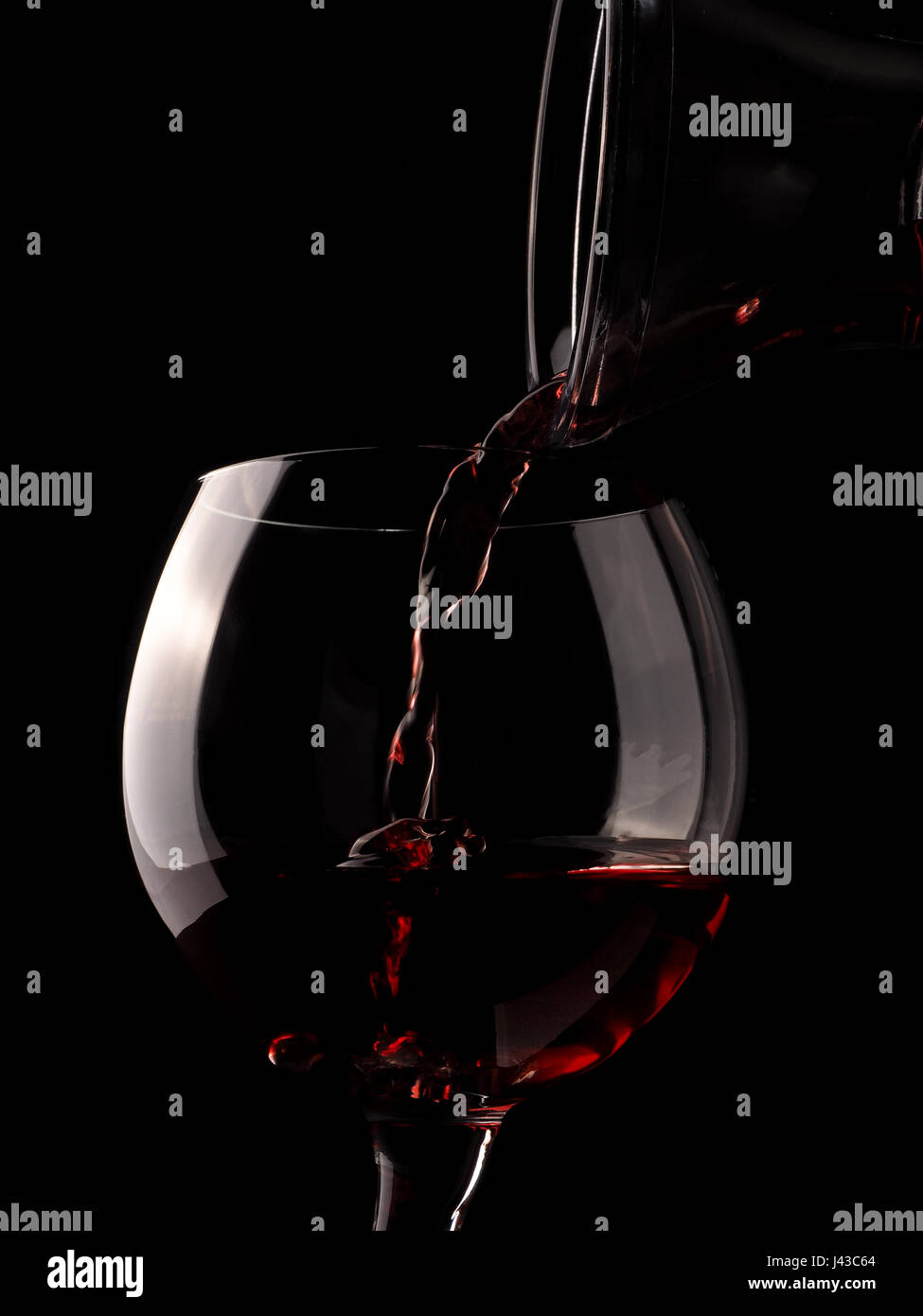 Glass of red wine with an old rustic decanter on a dark background ...