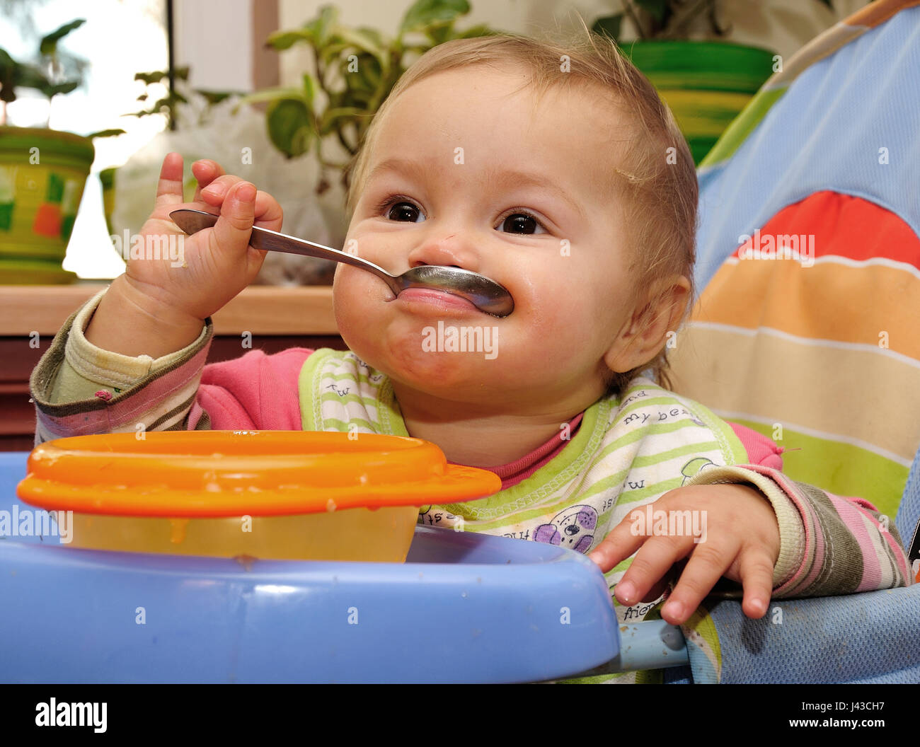 smiling baby eating food alone on kitchen Stock Photo - Alamy