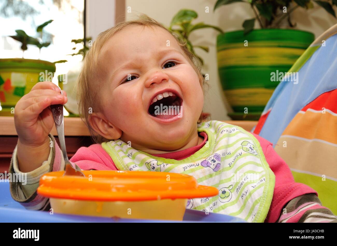 smiling baby eating food alone on kitchen Stock Photo - Alamy