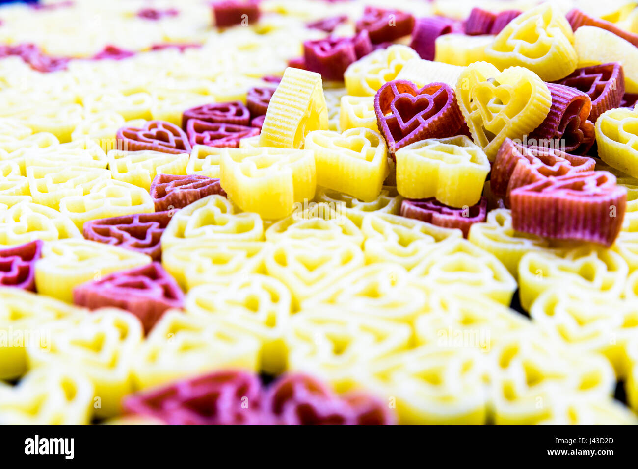 Red and yellow heart shaped pasta on blue background Stock Photo - Alamy