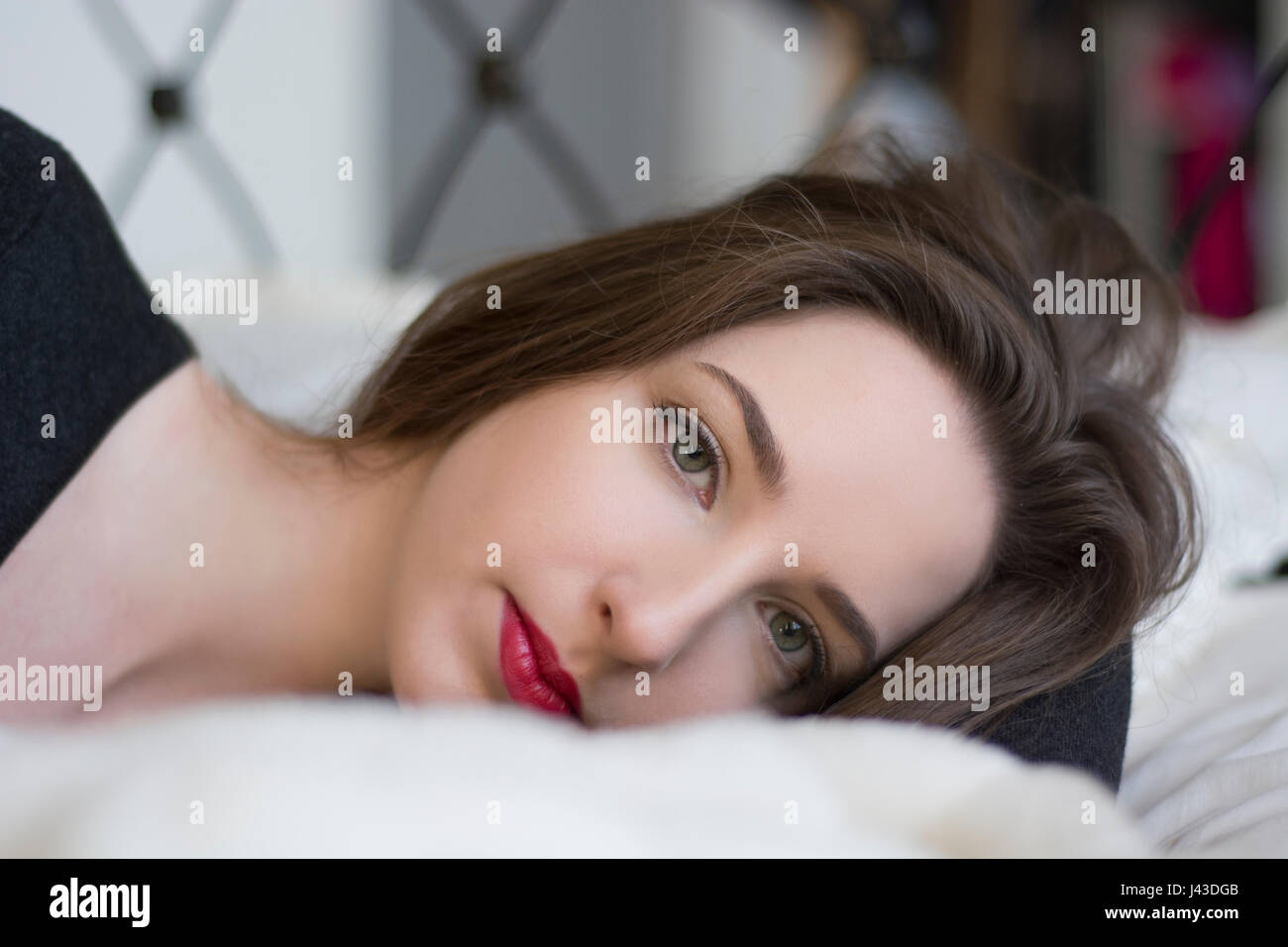 Beautiful young woman laying down in bed staring Stock Photo - Alamy