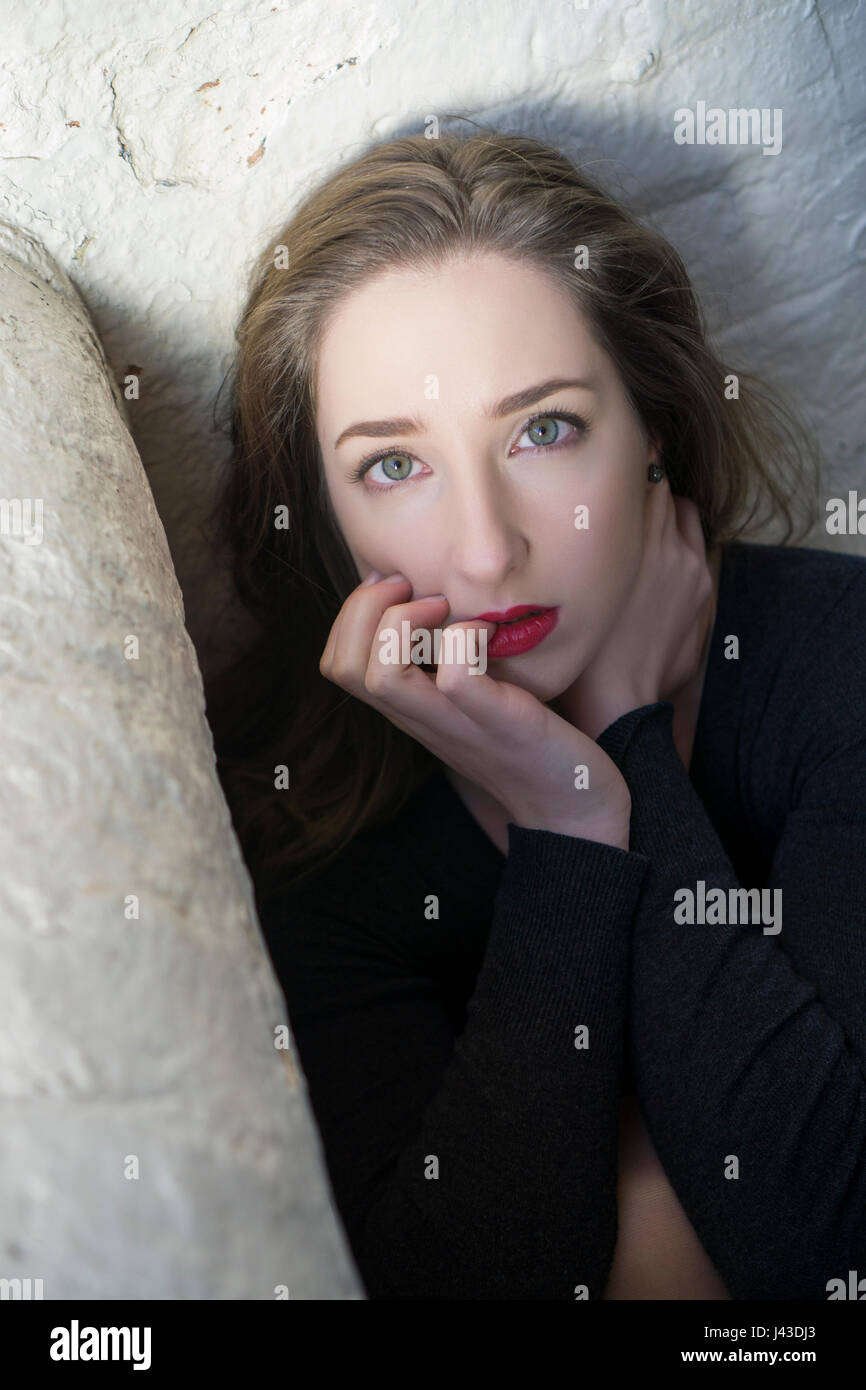 Scared young woman sitting down hands touching face Stock Photo - Alamy