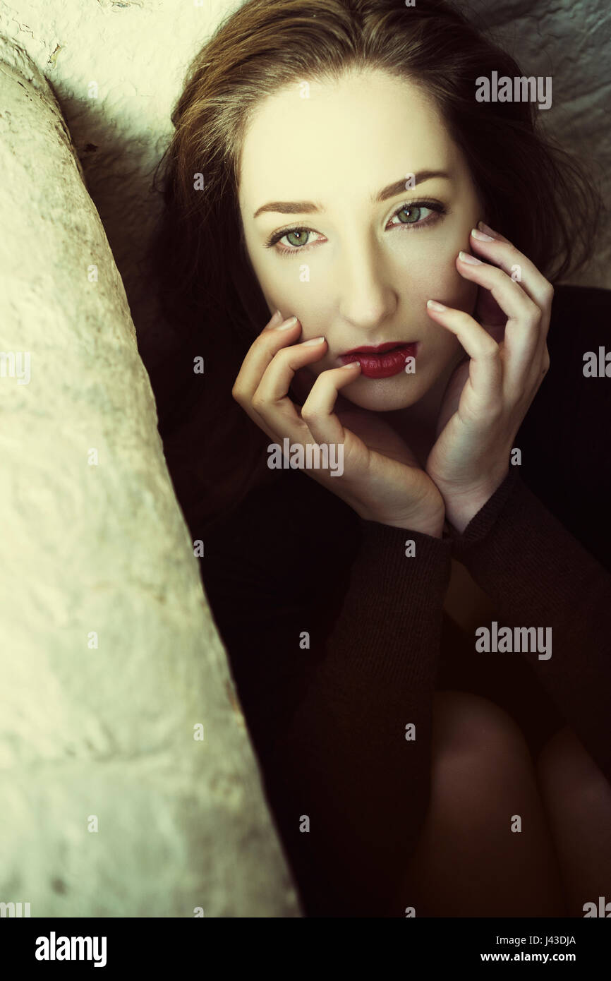 Scared young woman sitting down hands touching face Stock Photo - Alamy