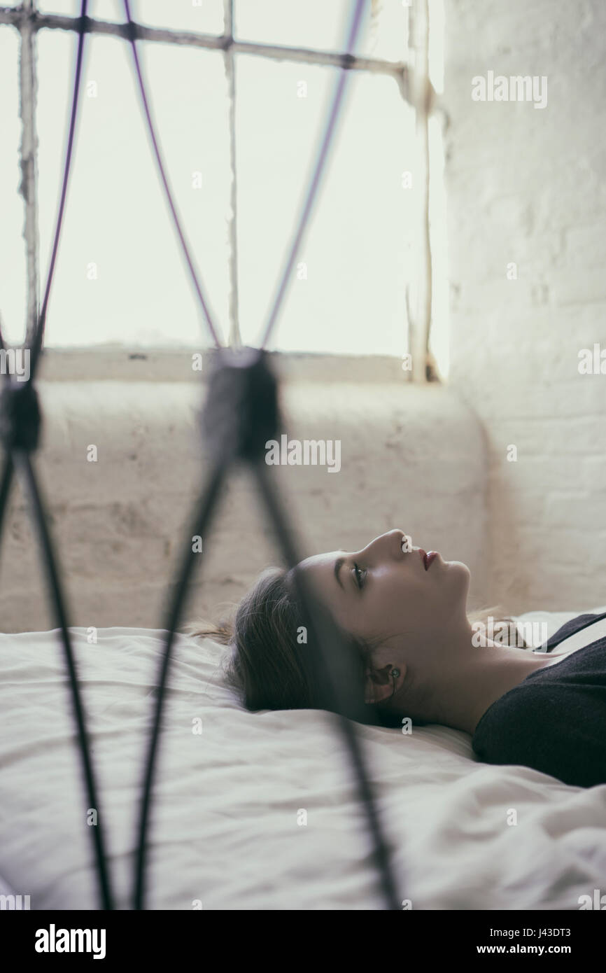 Sad young woman laying down in bed looking up Stock Photo - Alamy