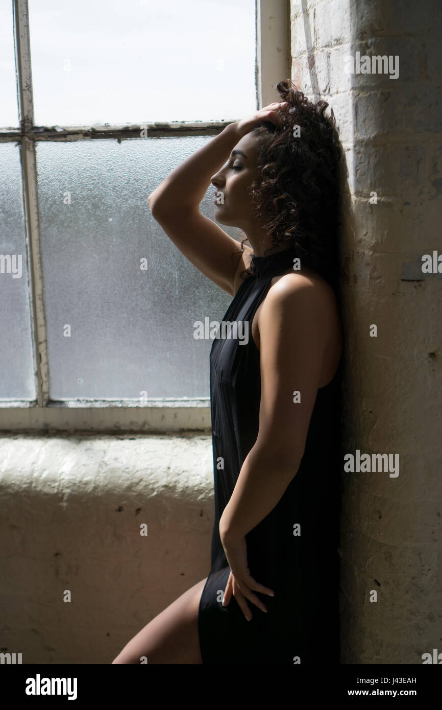 Sad young woman standing by the window Stock Photo - Alamy