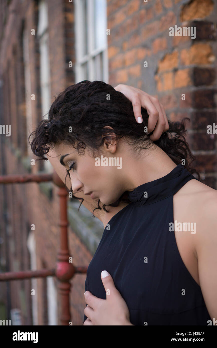 Sad young woman hand on head looking down Stock Photo - Alamy