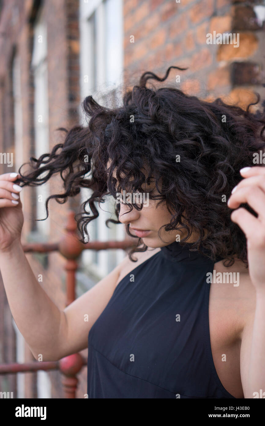 Portrait of a young woman hands pulling curly hair Stock Photo - Alamy