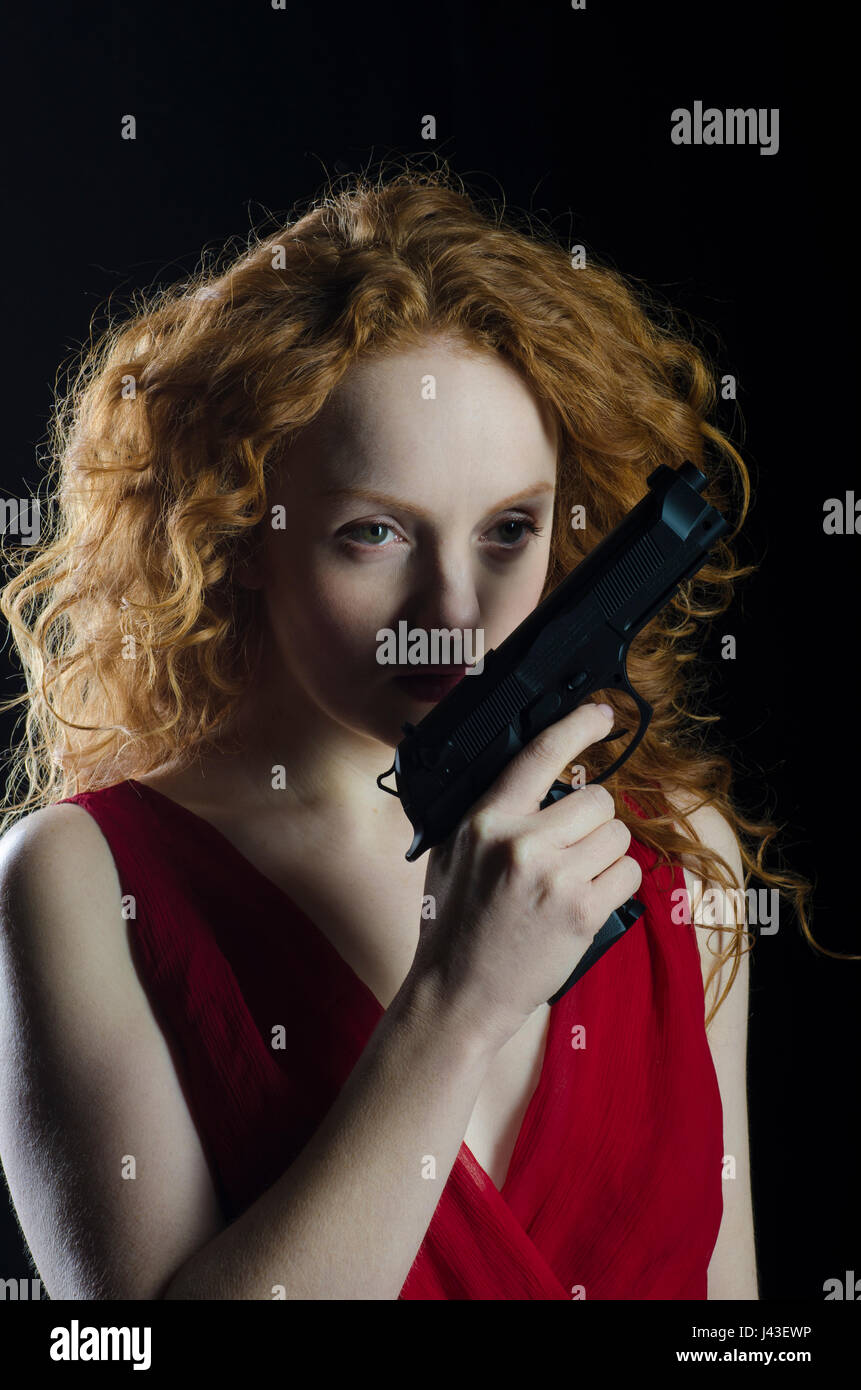 Beautiful woman holding a gun looking away Stock Photo - Alamy
