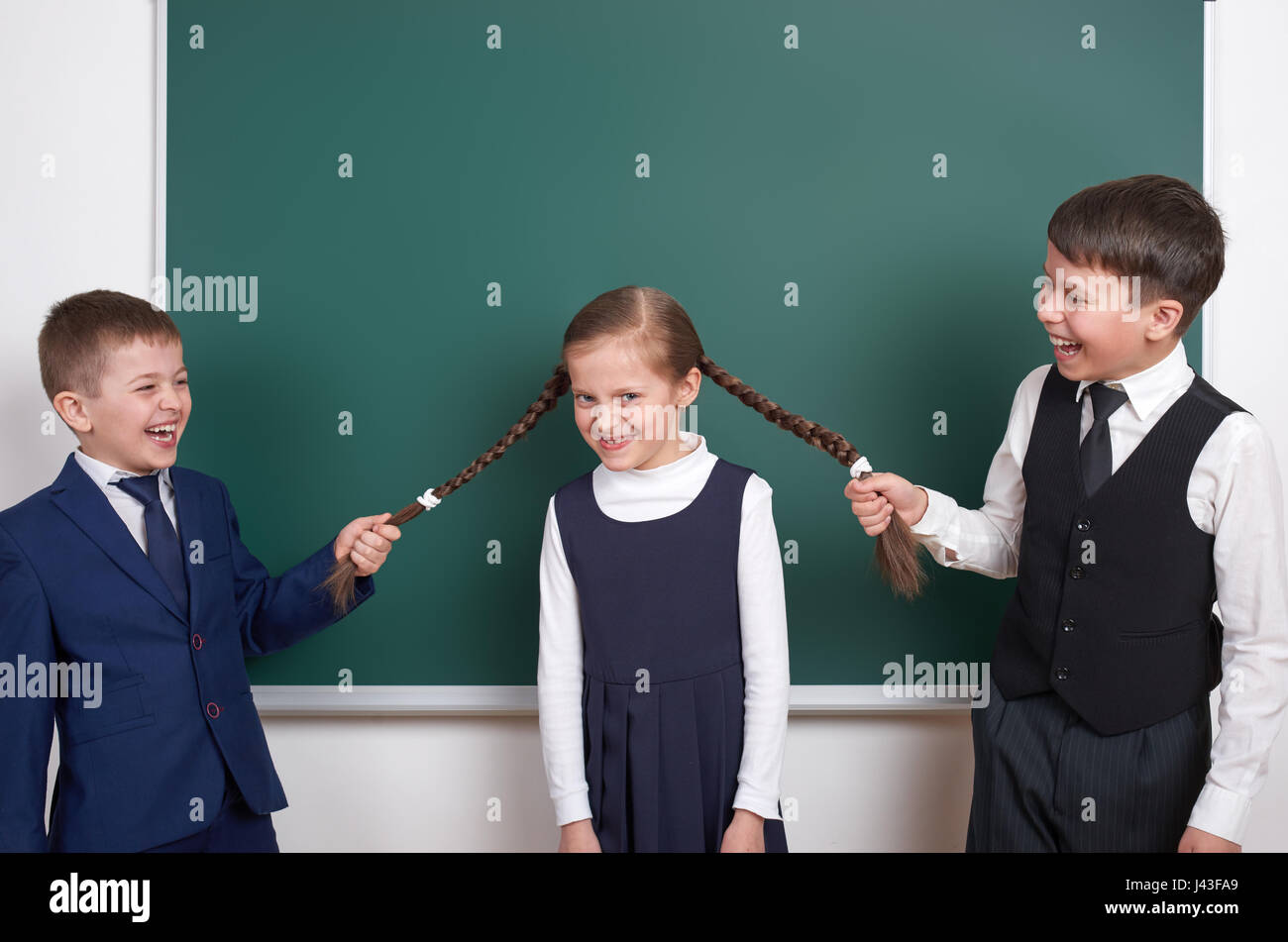 child play and having fun, boys pull the girl braids, near blank school ...