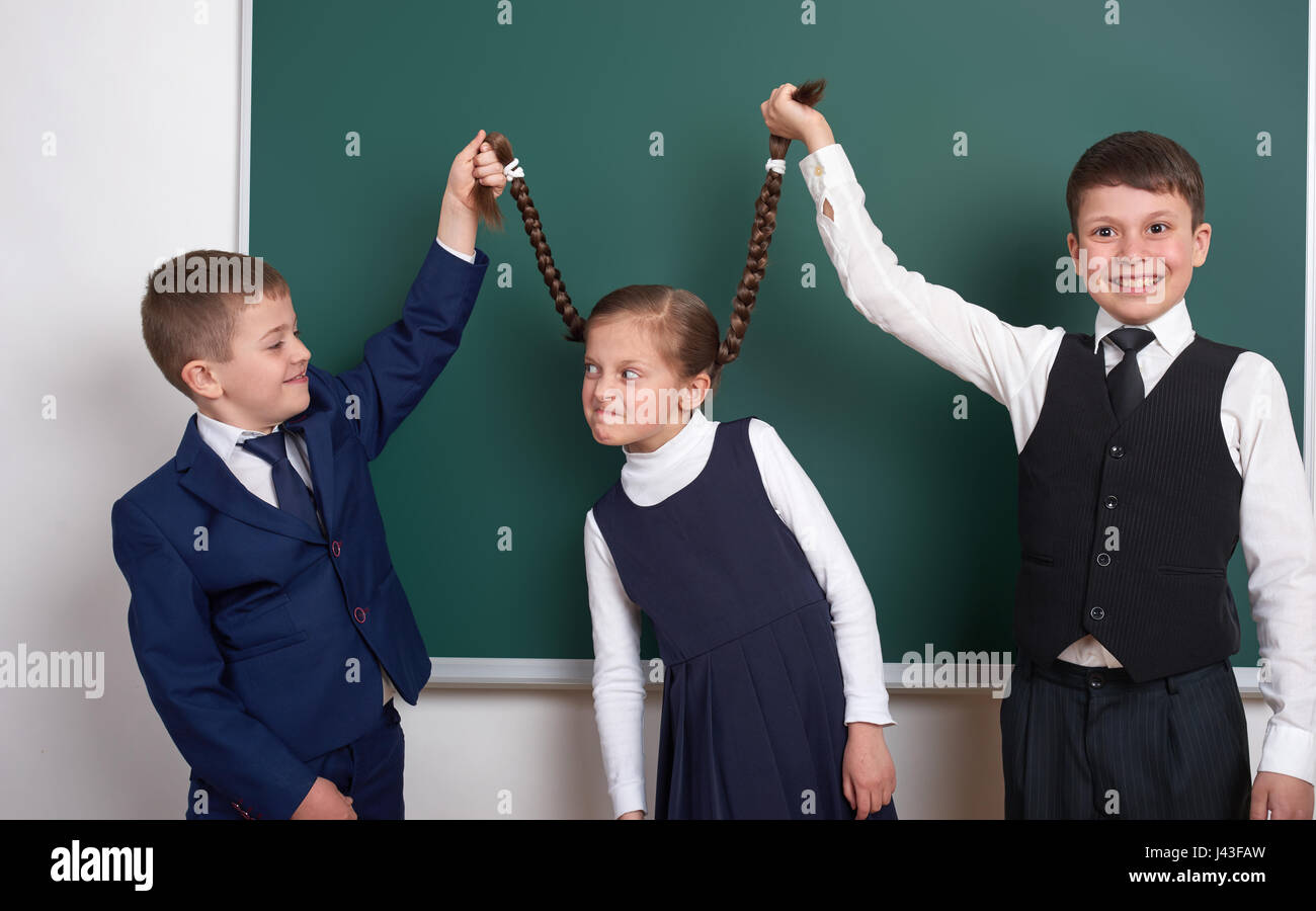 child play and having fun, boys pull the girl braids, near blank school ...