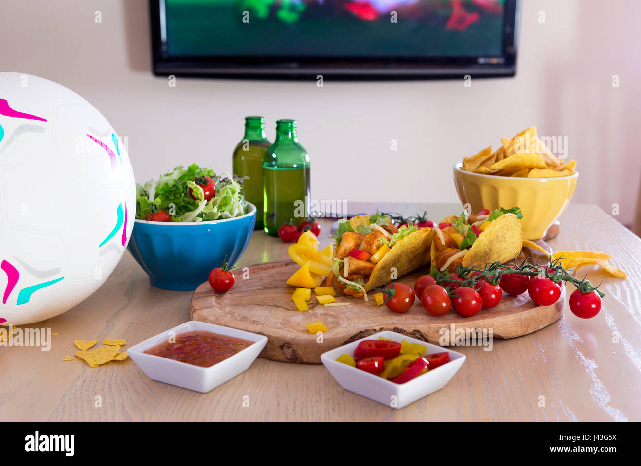 Mexican tacos and beer on a table with a football. There is a ...