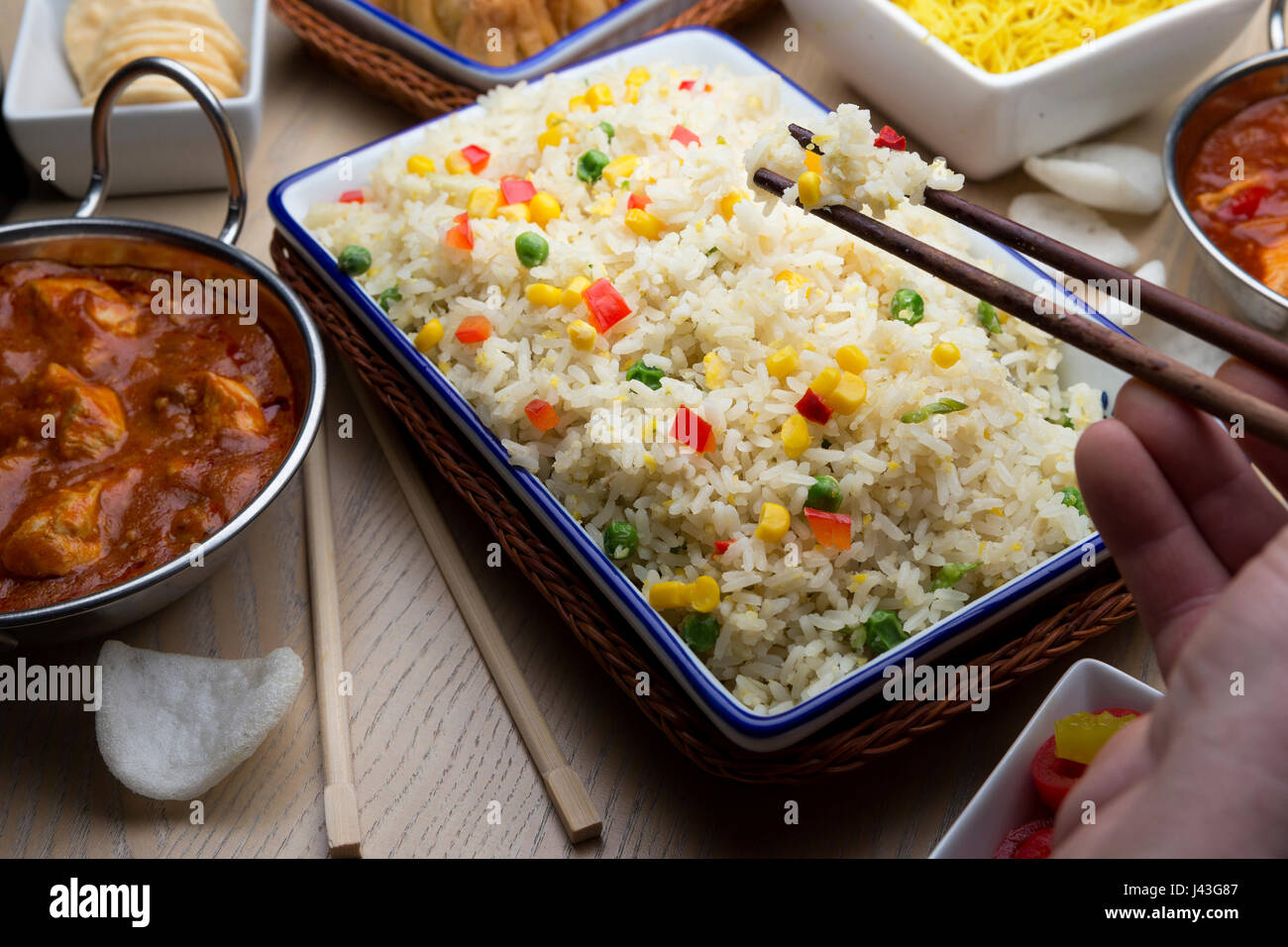Close up of a large tray of rice surrounded by chinese food. Someone is ...