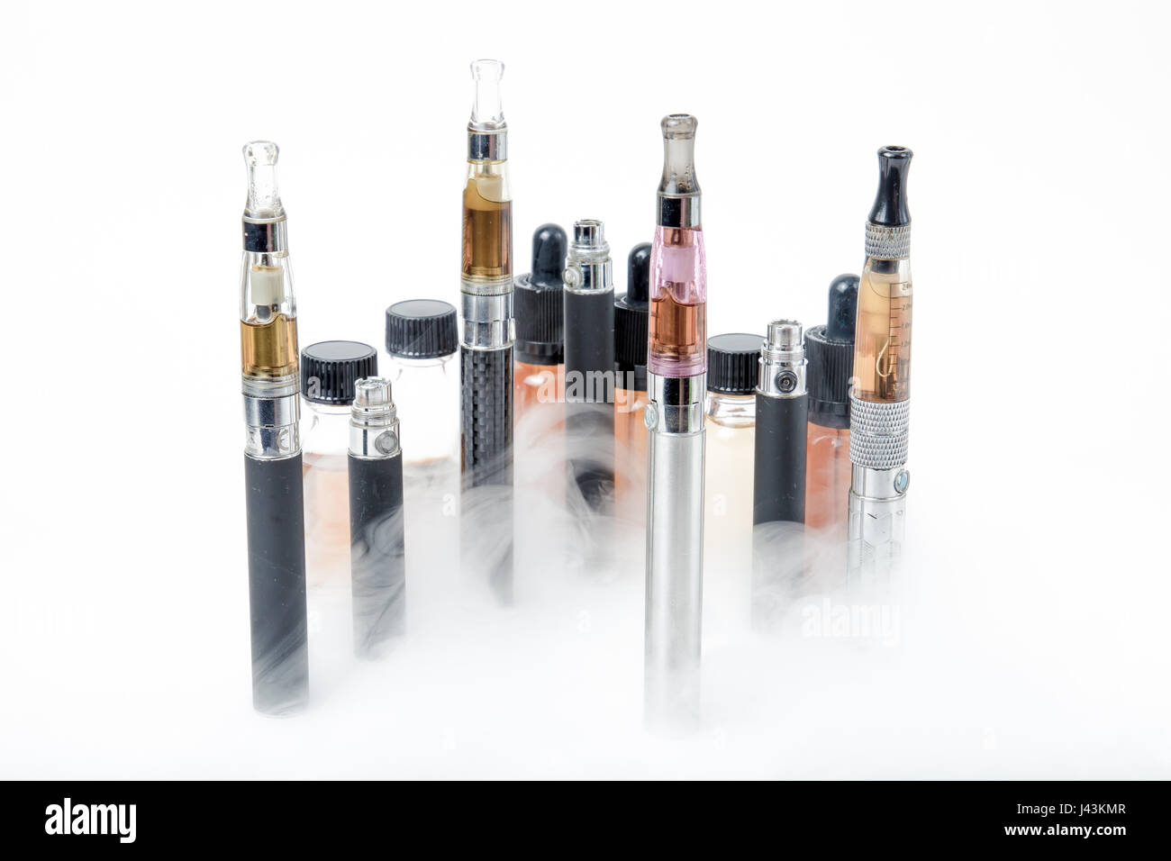 Thin e-cigarettes with glass bottles and smoke on white background ...
